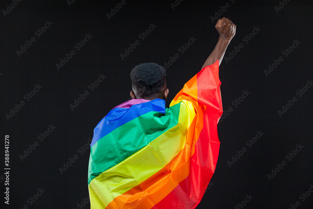 Back view of young african american man wrapped in a rainbow flag ...