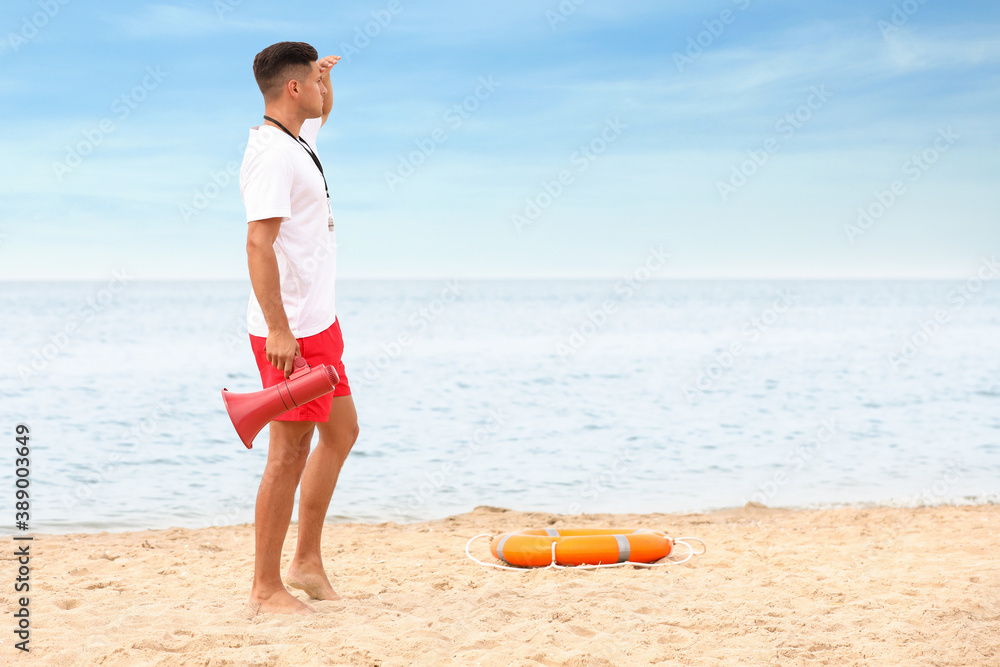 Handsome male lifeguard with megaphone at sandy beach Stock Photo ...