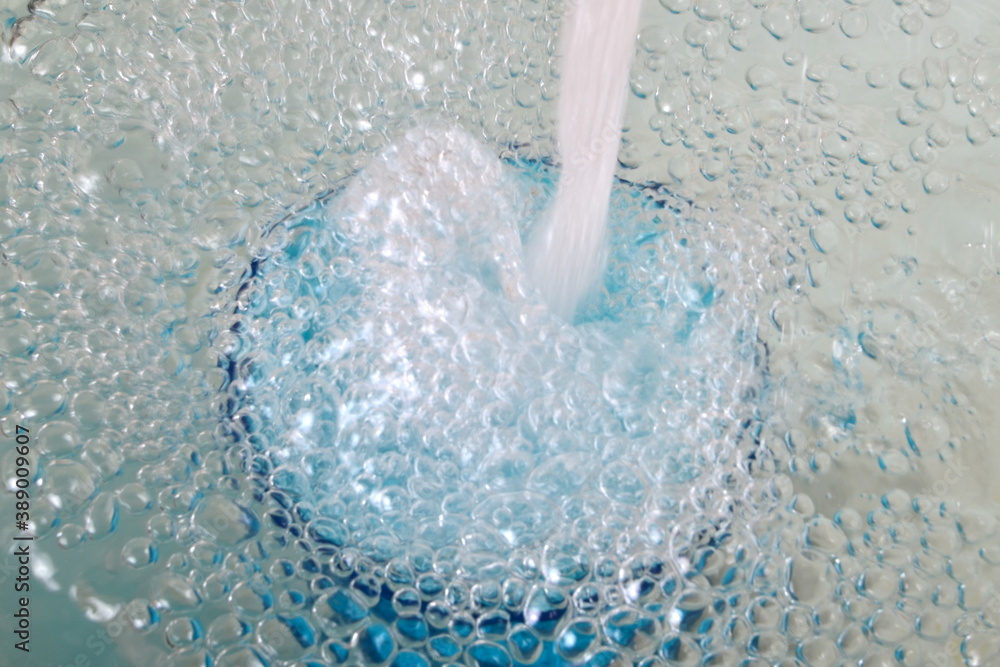 Overflowing water in a blue glass, full overflow glass with water and ...