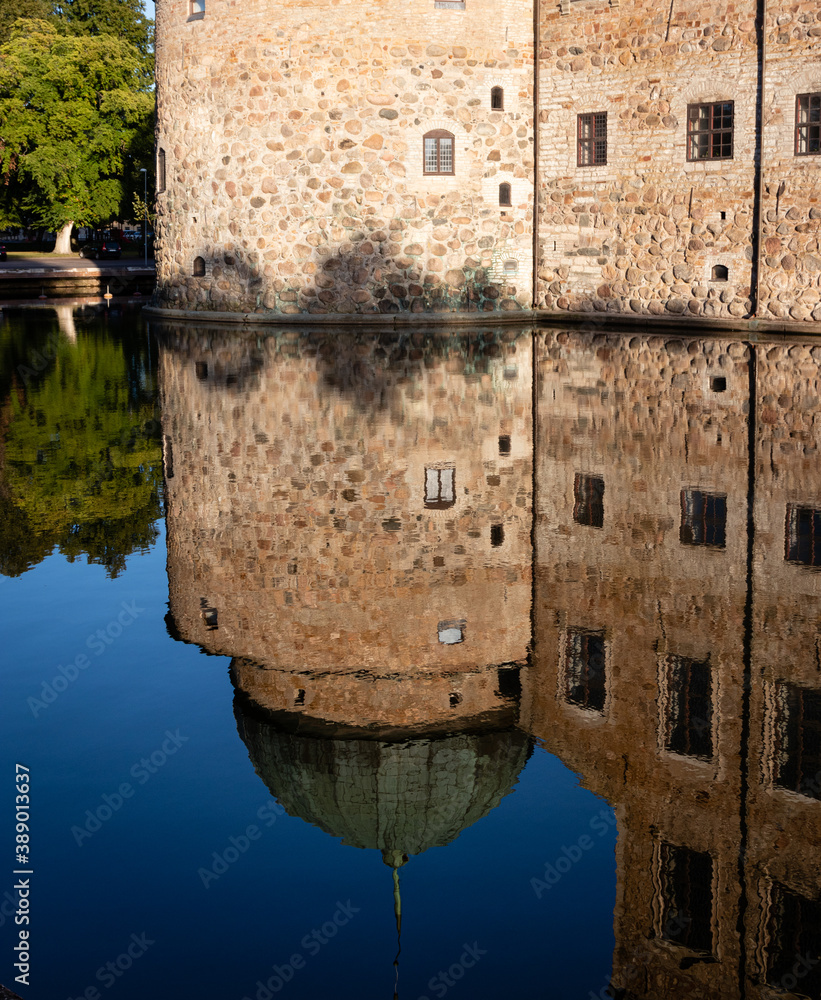 Medieval castle tower with windows reflecting in the water of the moat ...