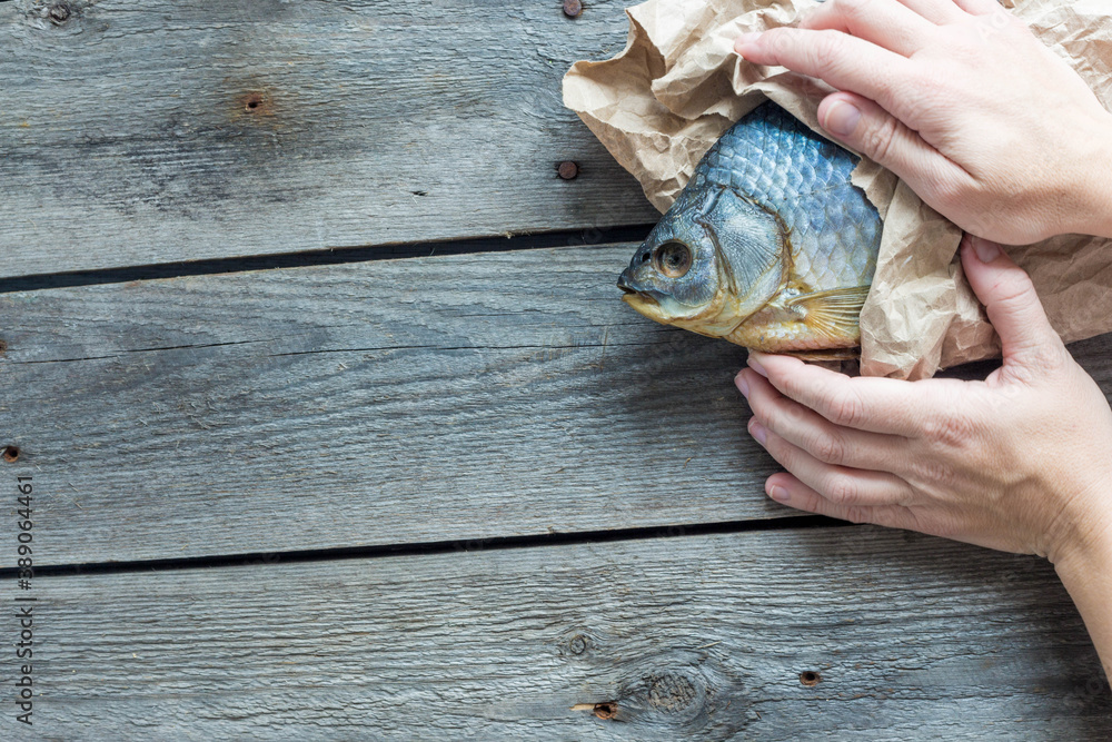 Hand holds Dried Volga bream vobla in a crumpled kraft paper roll Stock ...