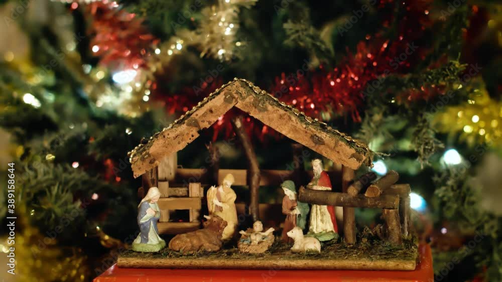 Woman puts miniature figurines of Mary in a christmas crib next to a ...