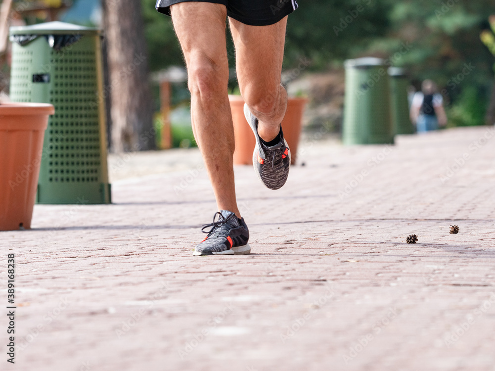 Athletic man wear running sneakers run. Hard red pavement and legs in ...