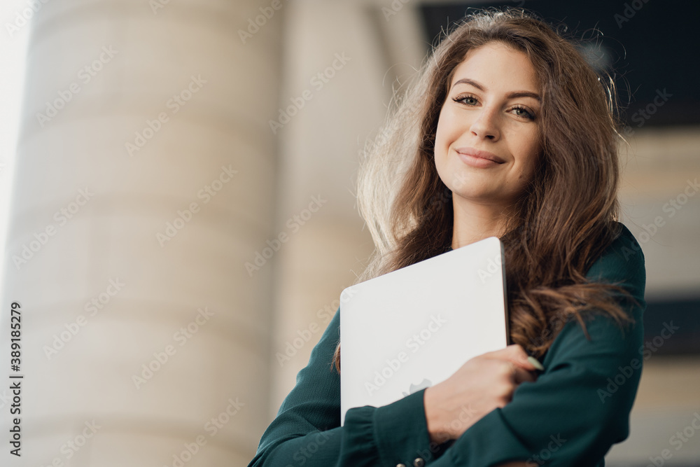 smiling in a green dress and looking at the camera. holds an office ...