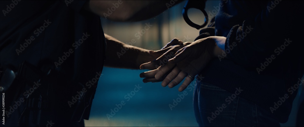 CLOSE UP Police officer handcuffs a suspect near police car, African ...