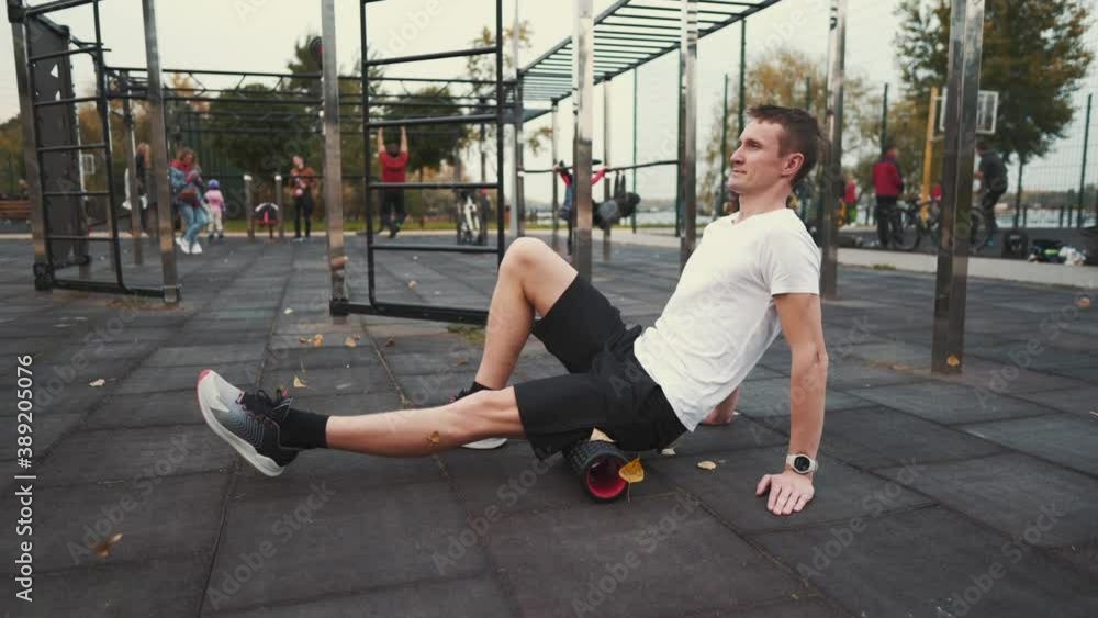 Caucasian man athlete doing exercises on myofascial roller massage leg ...
