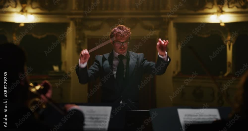 Cinematic close up shot of conductor directing symphony orchestra with ...