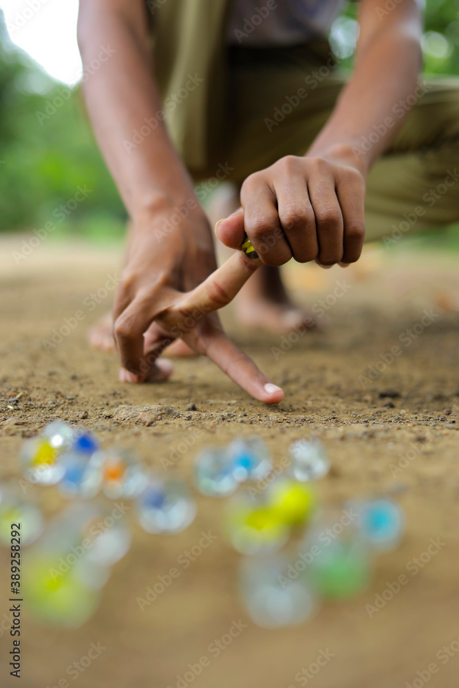 A child playing with glass marbles which is an old Indian village game ...