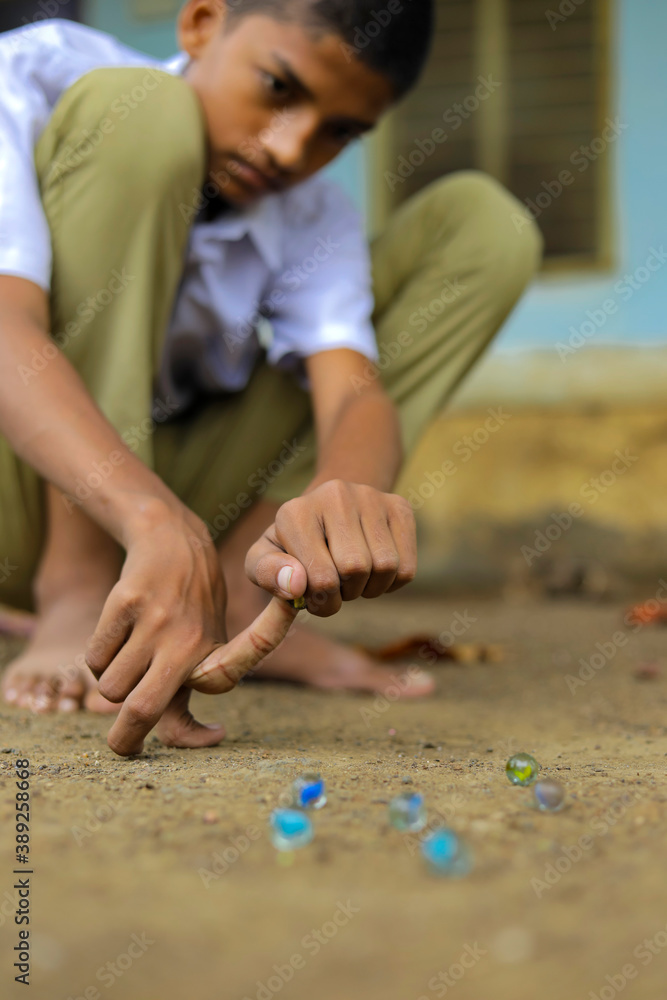 A child playing with glass marbles which is an old Indian village game ...
