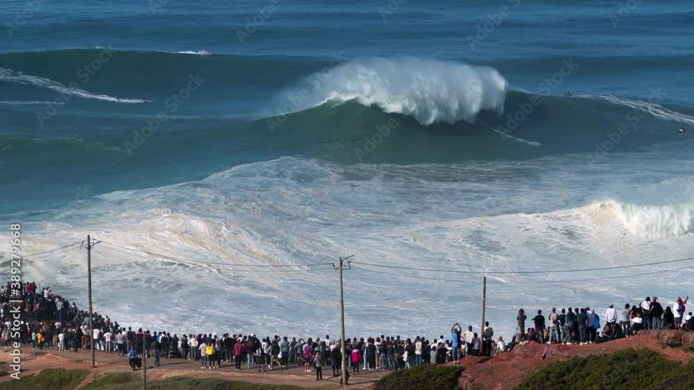People watching big wave surfers riding giant waves near Praia do Norte ...
