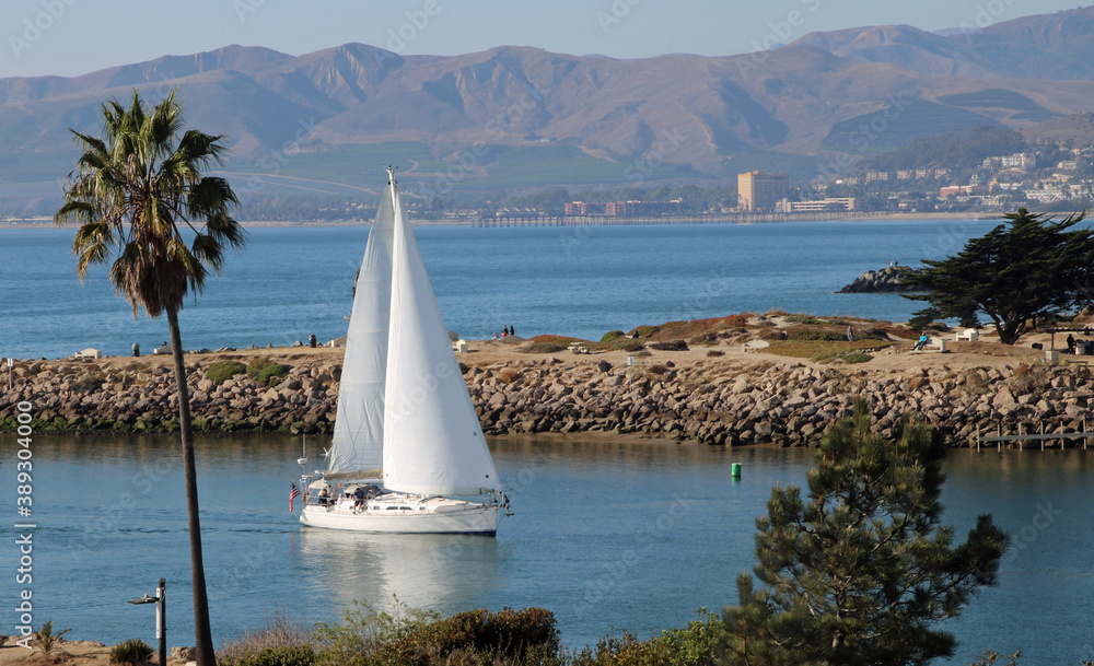 Sailboat entering harbor with mountains in background Stock Photo ...