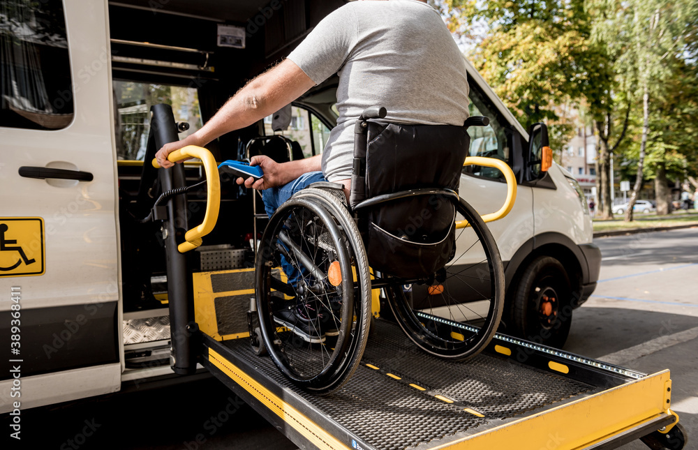 A man in a wheelchair on a lift of a vehicle for people with ...