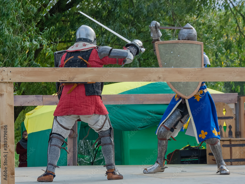 Two foot warriors in heavy medieval armor fight in the arena. Armed ...