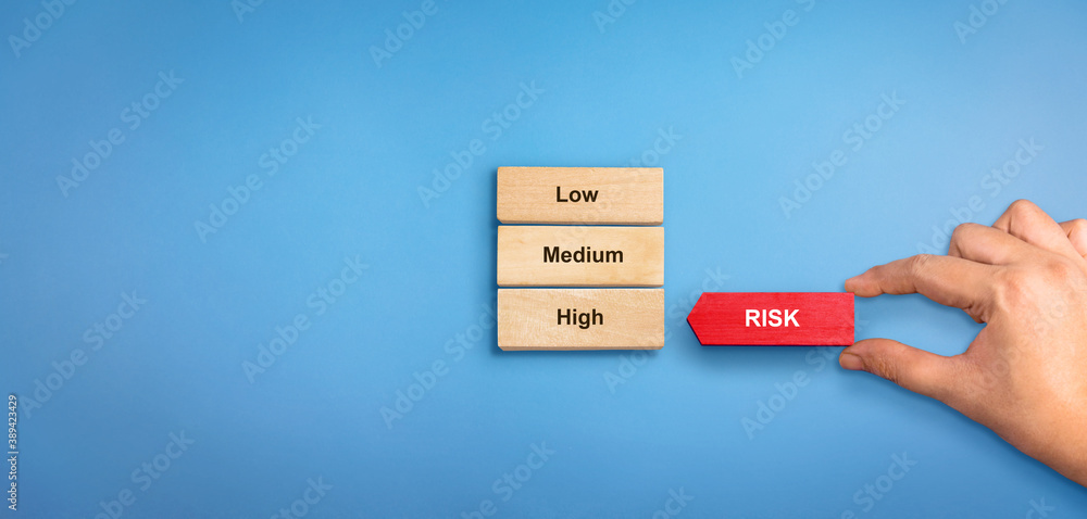 Risk concept with text high, medium and low. Hand holding wooden block ...