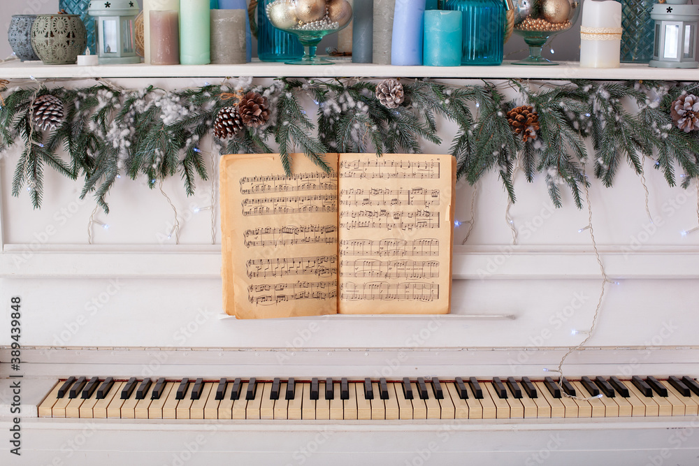 White piano with music book. Piano decorated branches of a Christmas ...
