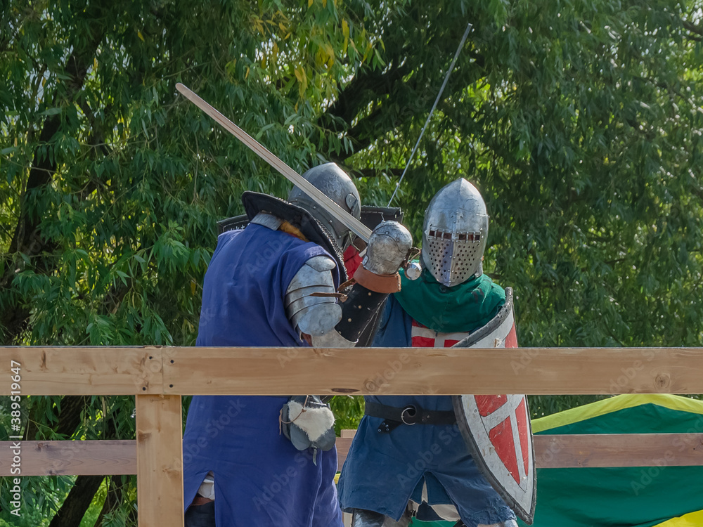 Two foot warriors in heavy medieval armor fight in the arena. Armed ...