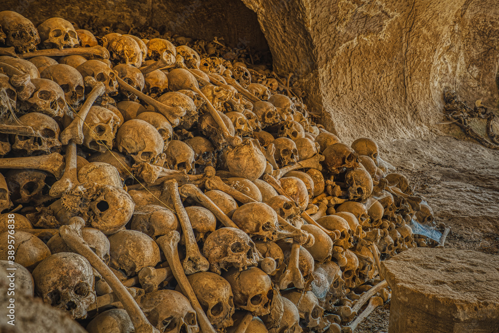 Spooky detail of a pile of skulls and bones in a crypt bears death and ...