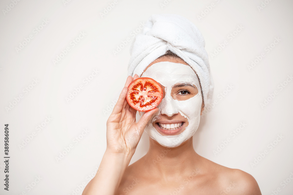 Beauty young woman applying fresh treatments with fresh sliced tomatoes ...