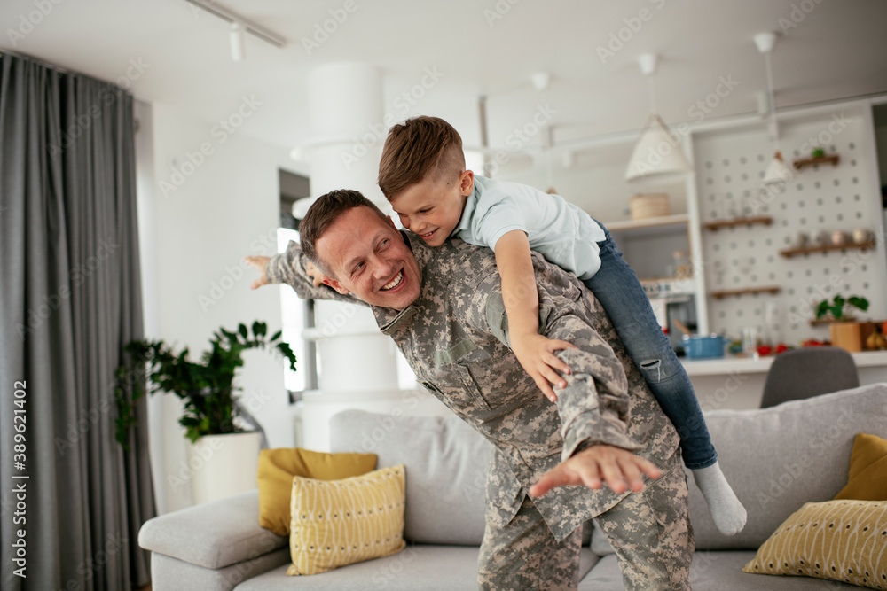 Soldier having fun with his son at home. Father and son playing in ...