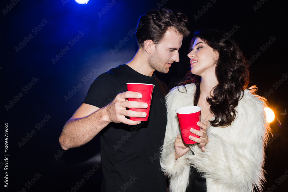 Passionate man looking at woman lips, hugging, holding plastic cup with ...
