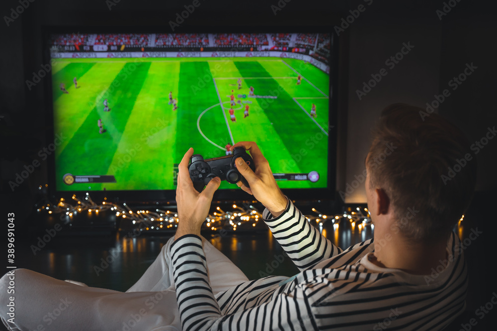 Young hipster man playing video game football soccer on console. gamer ...