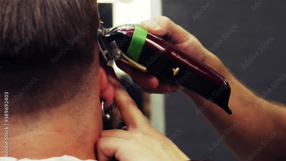 A Barber man does his hair with a hair clipper. Cut hair at the temples ...