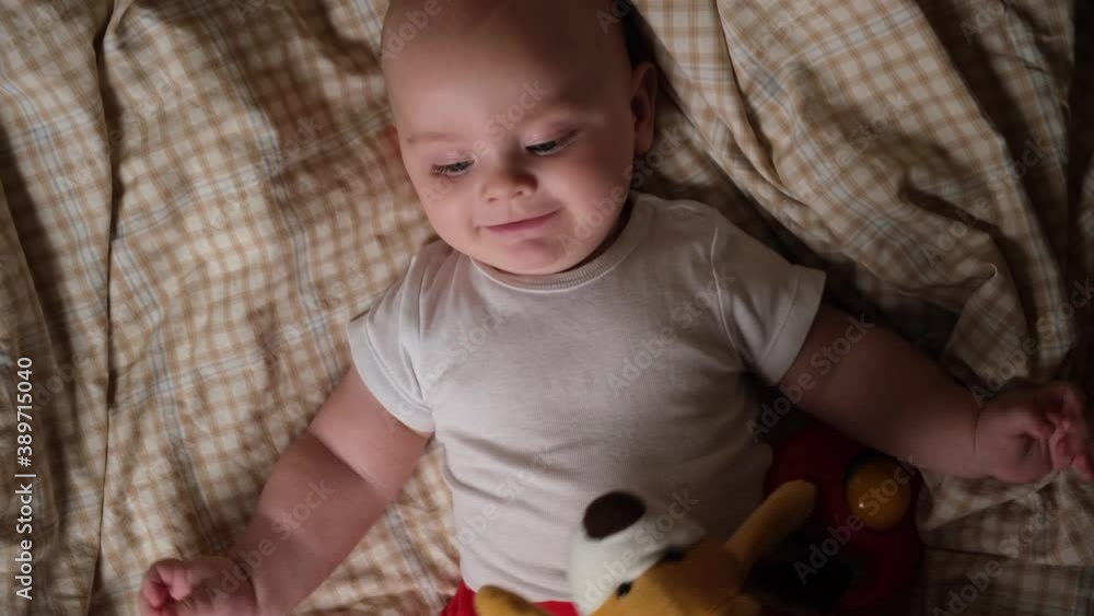 Parent playing with child. Infant boy lying in bed, mother wearing hand ...