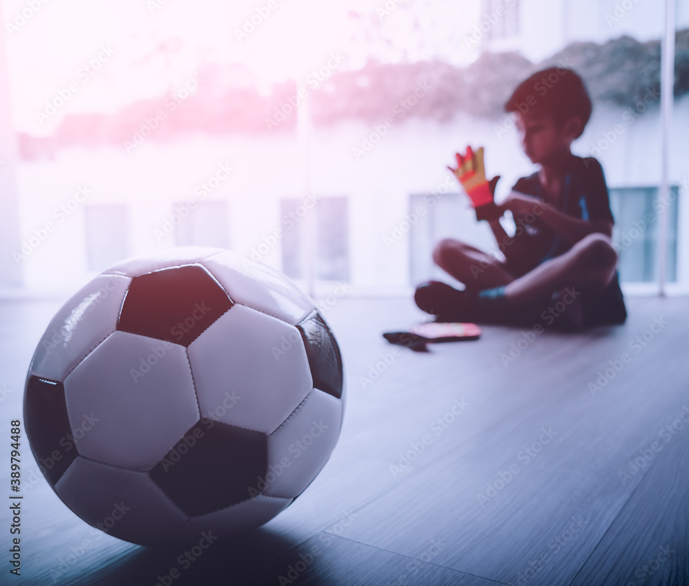 Little Football goalkeeper boy is sitting and relaxing with soccer ball ...