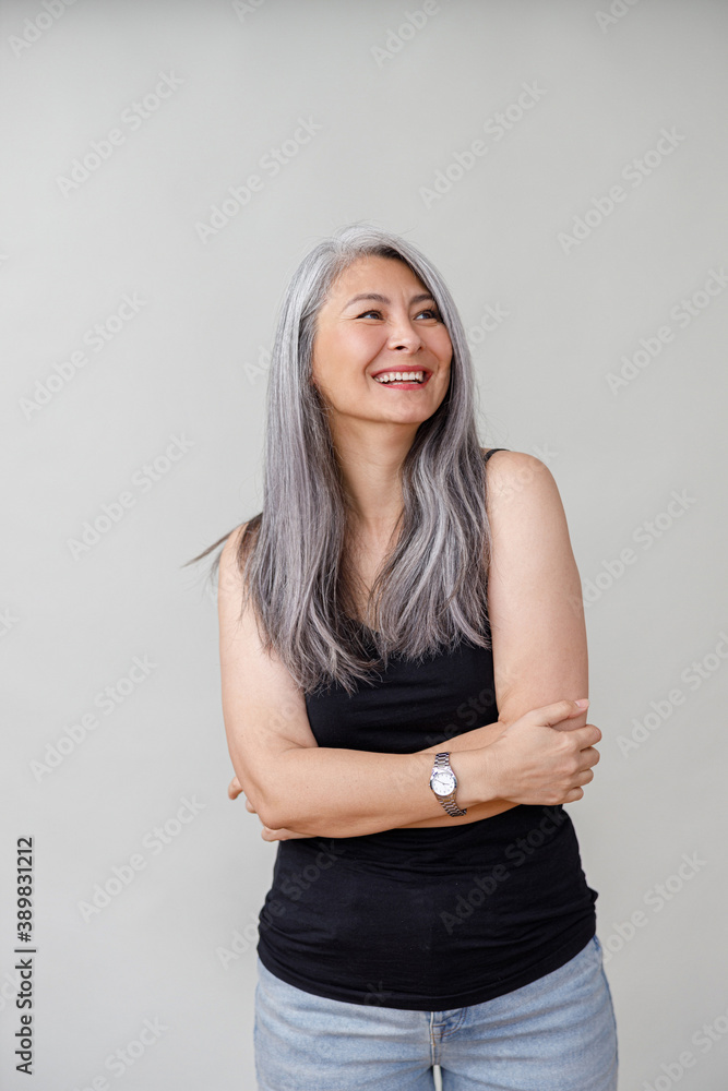 Emotional portraits of a paled long hair asian matured woman on grey ...