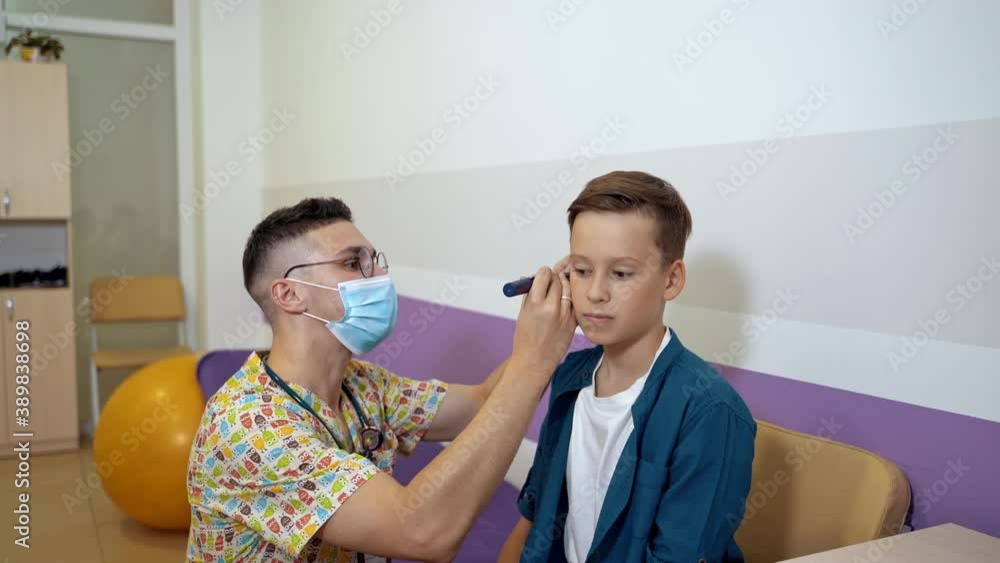Doctor Examining Boy Ear. Doctor auscultating the ear of child with ...