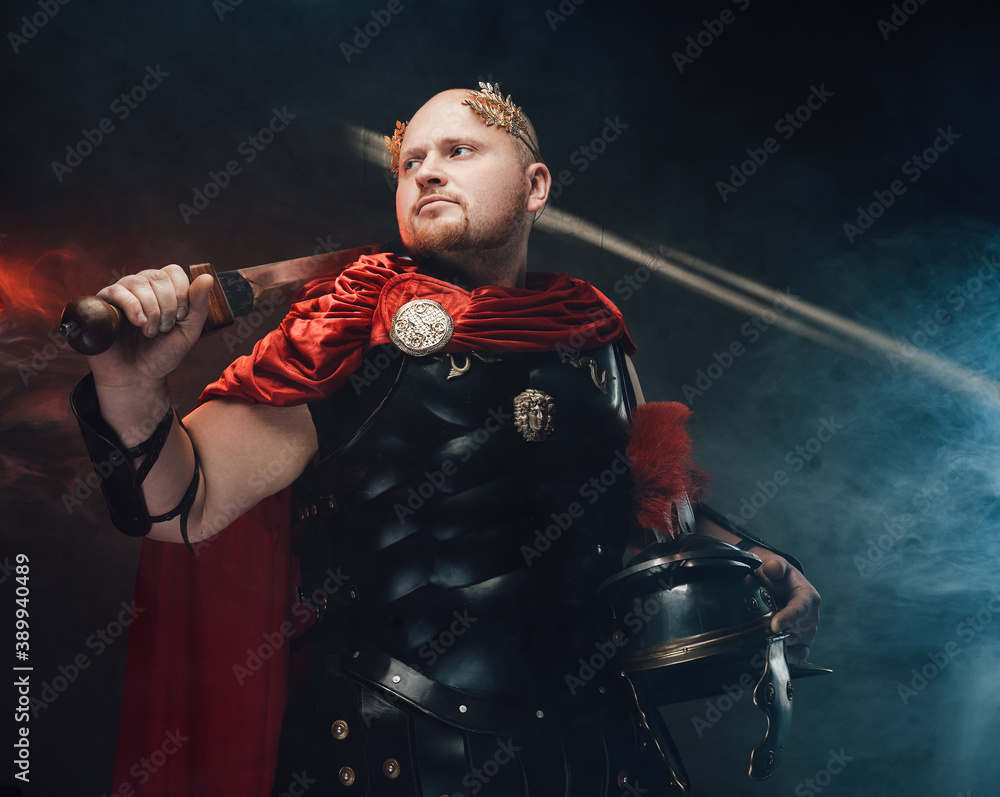 Handsome hairless roman soldier in dark armour and red cape poses ...