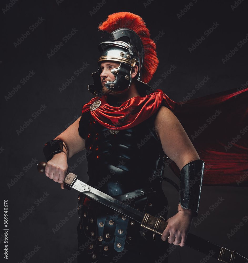Handsome and warlike legionary in black armour with red cape and helmet ...