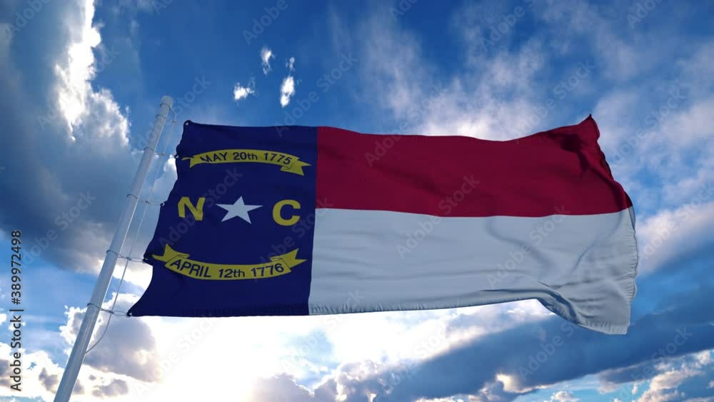 North Carolina flag on a flagpole waving in the wind, blue sky ...
