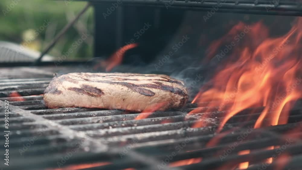 Man roasts meat on grill. with tongs, puts piece juicy pork meat on hot ...