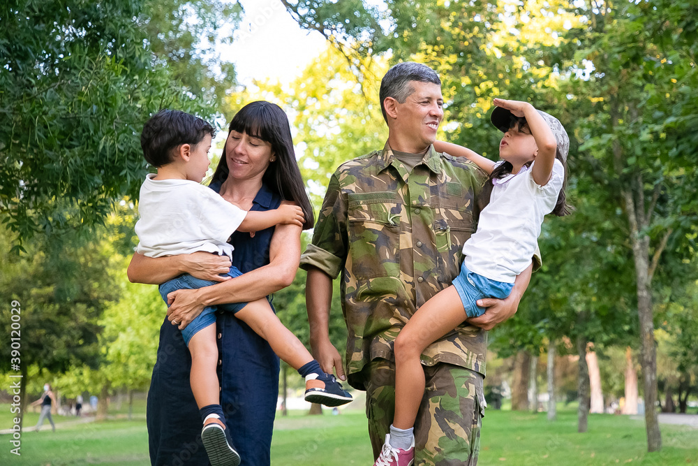Happy military man walking in park with his wife and kids, teaching ...