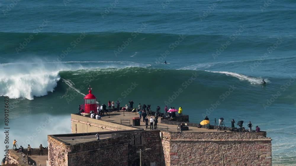 Surfer riding giant wave near historical landmark Fort of Sao Miguel ...