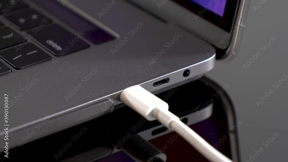 Close-up shot of hand inserting USB Type C wire into laptop computer on ...