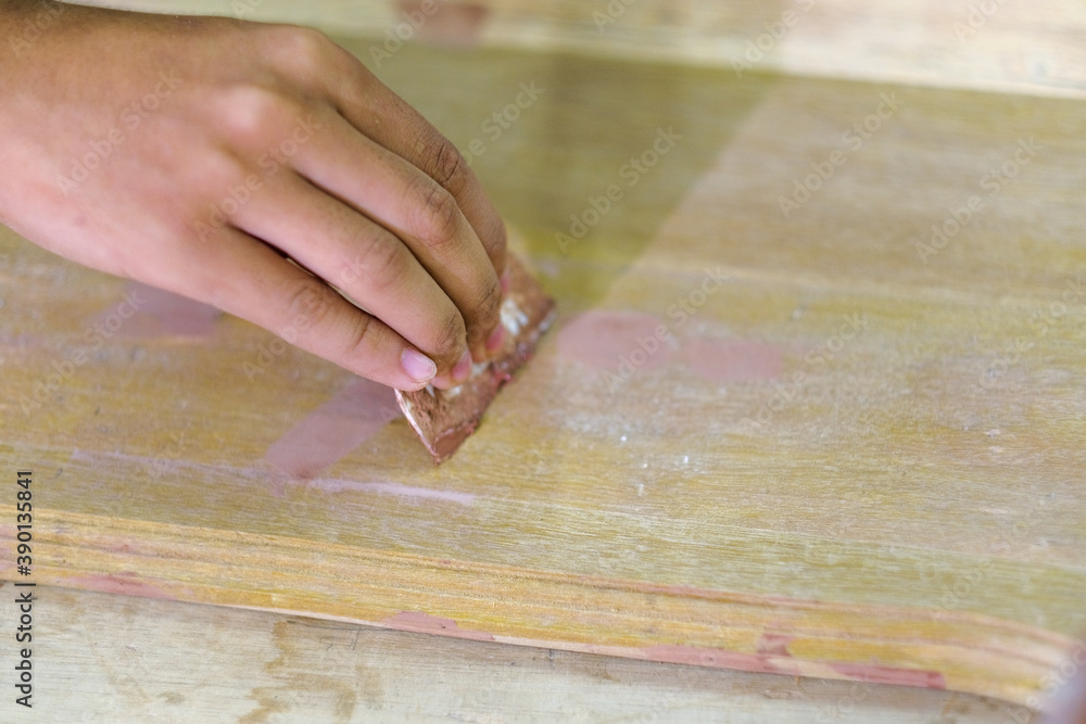 Young carpenter in work clothes and face mask using wood filler in ...