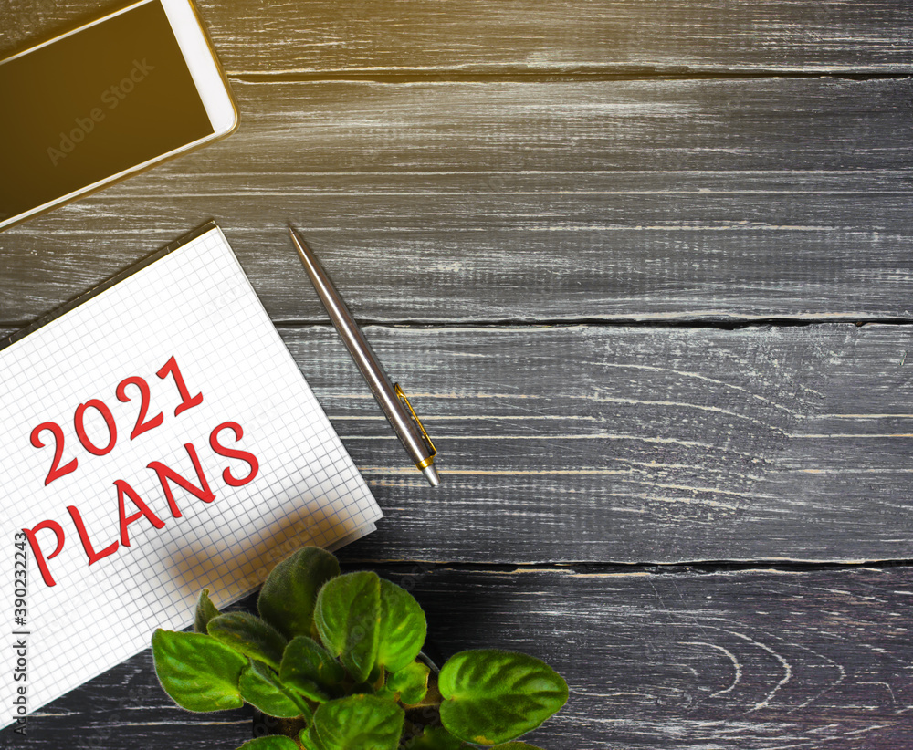 2021 Plans concept. Desktop with notebook, phone, pen. Planning goals ...