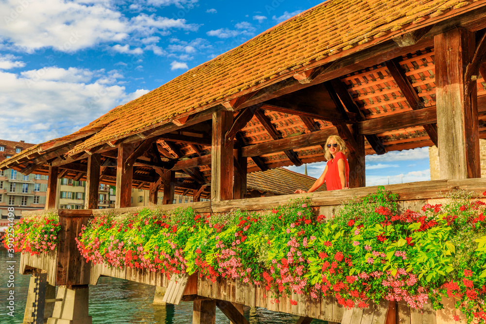 Blonde woman in red on the flowery bridge of Lucerne city, Reuss river ...