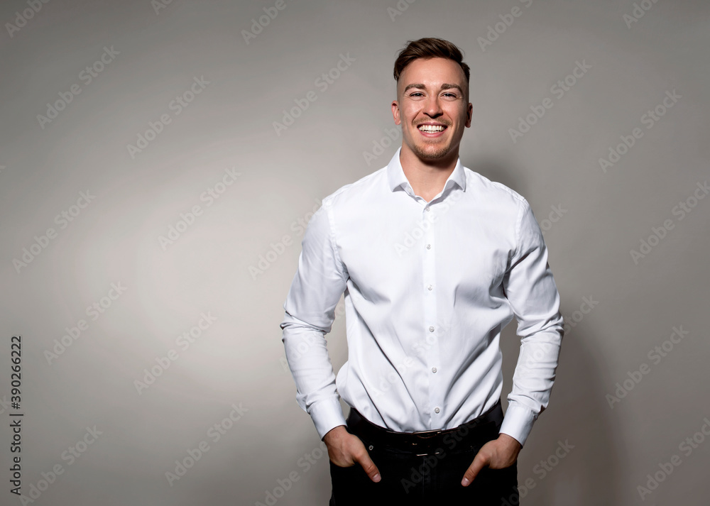 Handsome young man posing on grey background in white dress shirt while ...