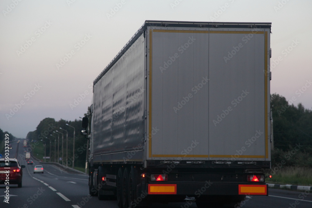 European gray van truck with semi trailer drive on two lane suburban ...