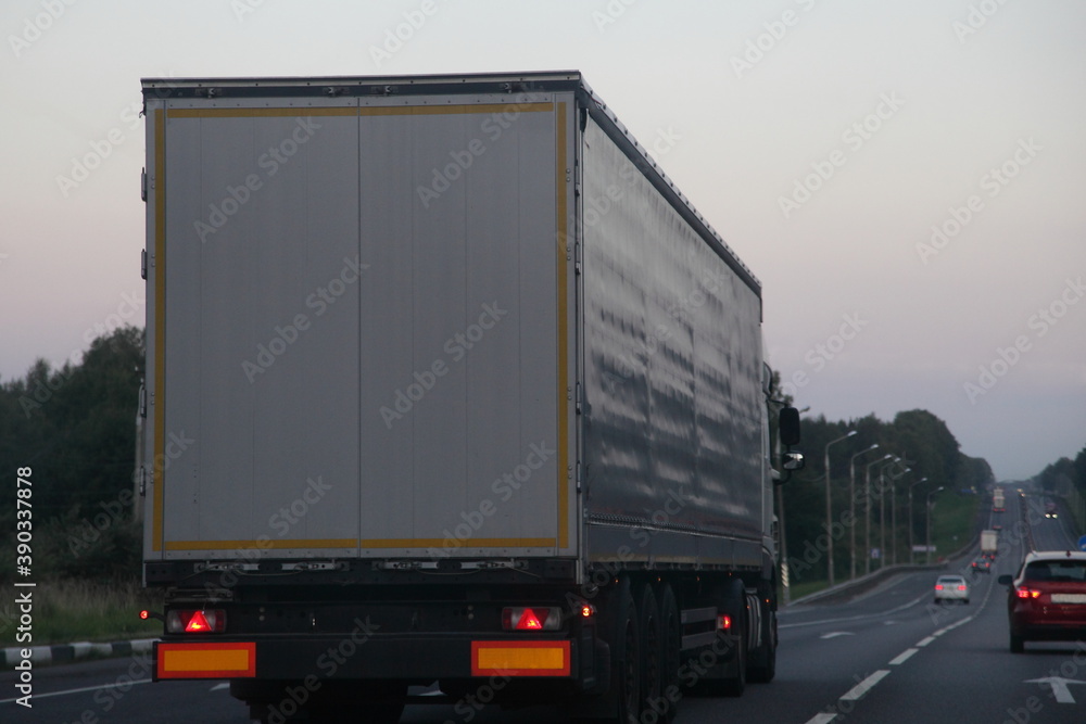 European van truck with gray semi trailer drive on two lane suburban ...
