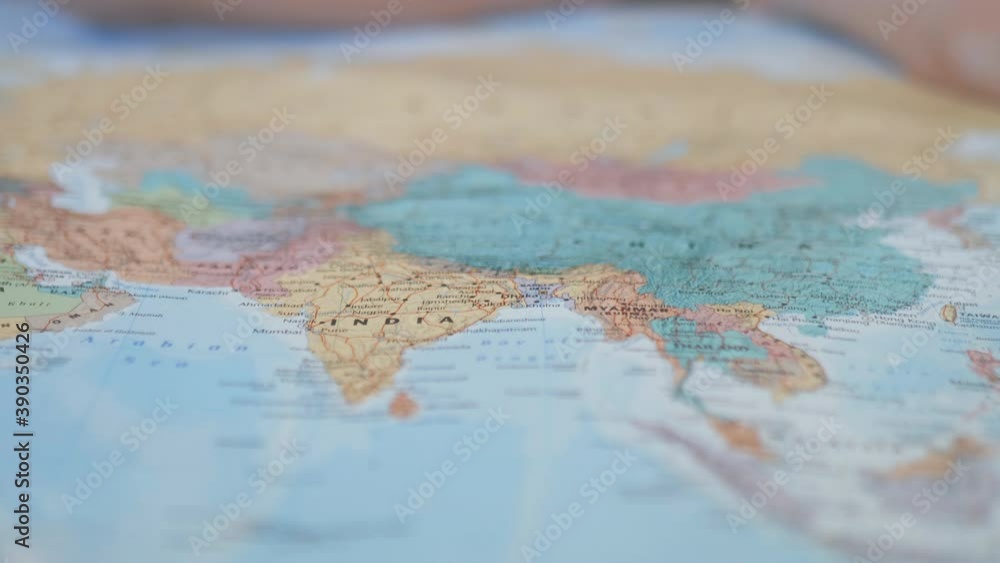 Blurry and colorful map of Asia with a hand pointing at it with a pink ...