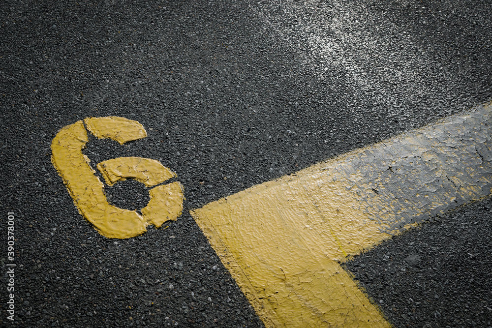 sign on the asphalt, yellow painted number six on grey street, yellow ...