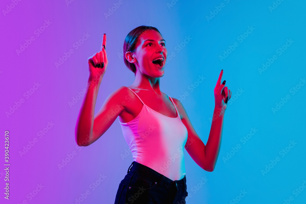 Pointing up. Young caucasian woman's portrait on gradient blue-purple ...