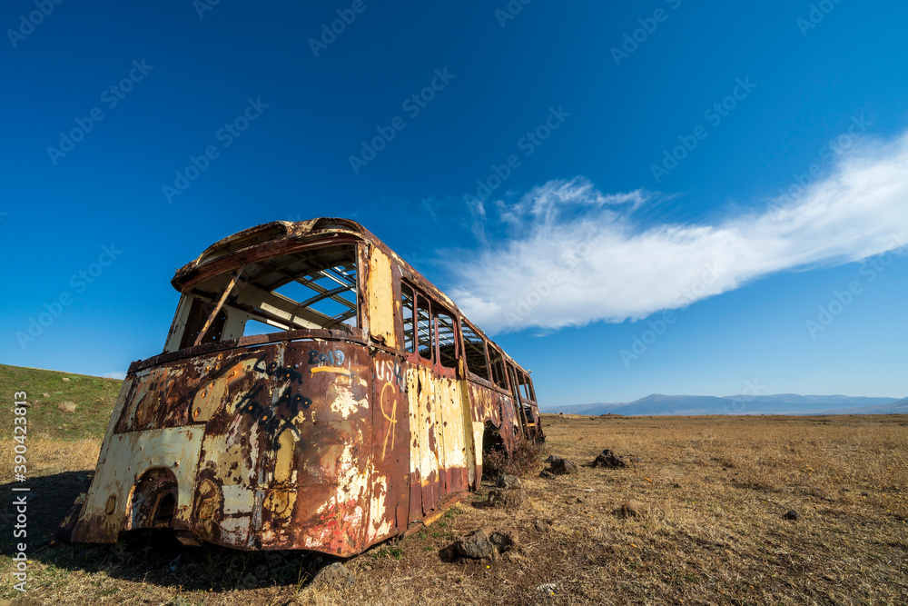 An old wreck of a bus on a field in Armenian countryside. Transport ...
