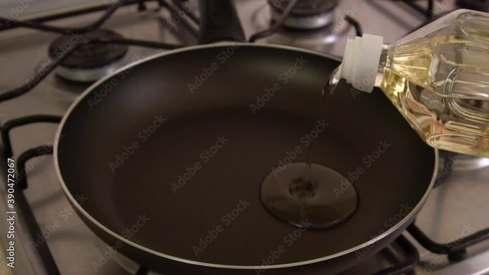 Pouring cooking oil into frying pan, slow motion close up.Pouring olive ...