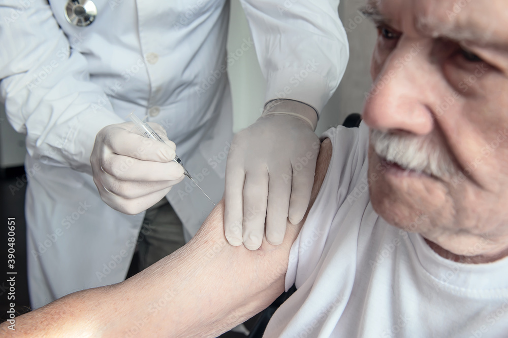 medical worker gives an injection with the covid-19 vaccine to an old ...