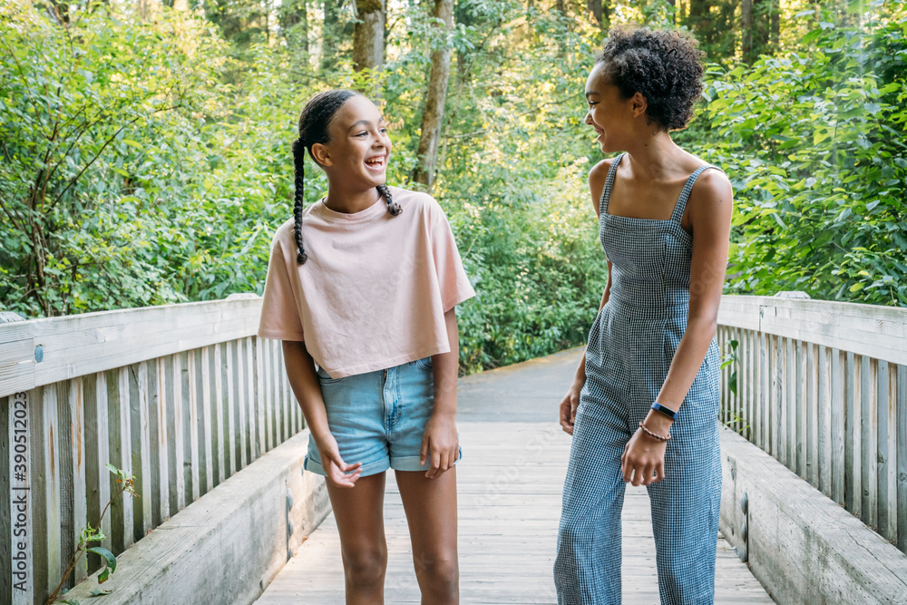 Teen girls walking and laughing together on bridge in nature park foto ...